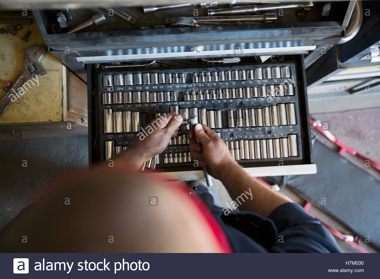 Overhead view of male mechanic choosing drill bit from tool box in ...