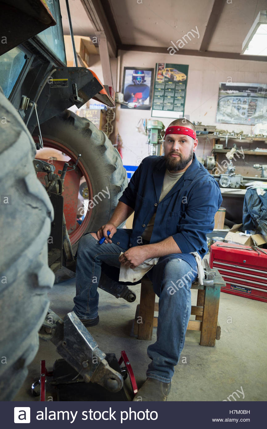 Portrait confident mechanic working on tractor in workshop Stock Photo ...