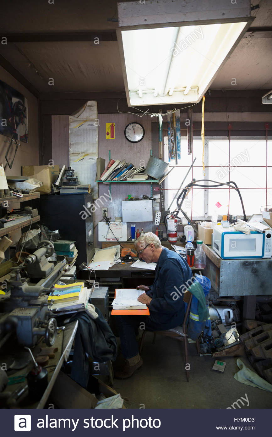 Senior male mechanic doing paperwork in workshop Stock Photo - Alamy