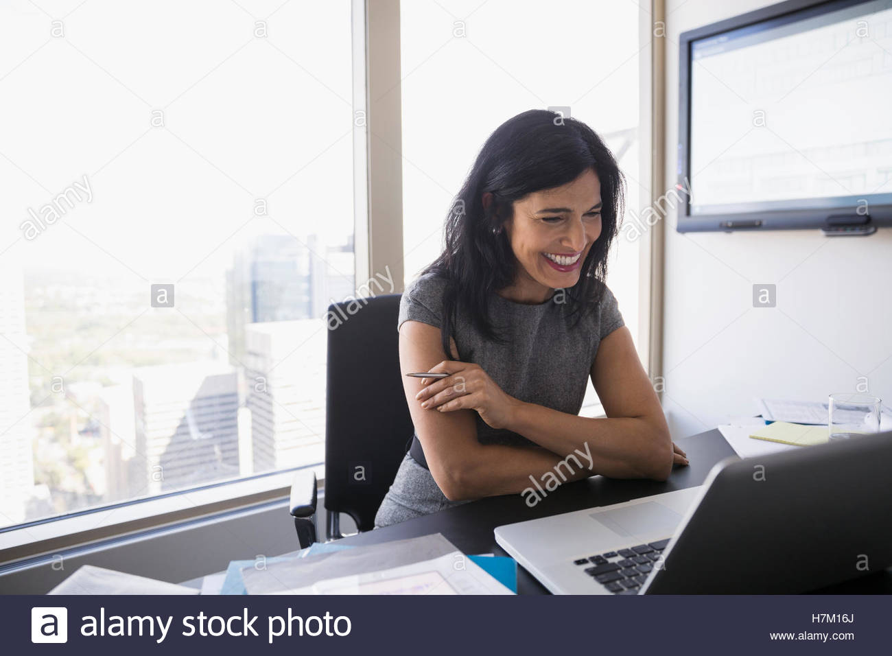 Smiling woman video conferencing at laptop in conference room Stock ...