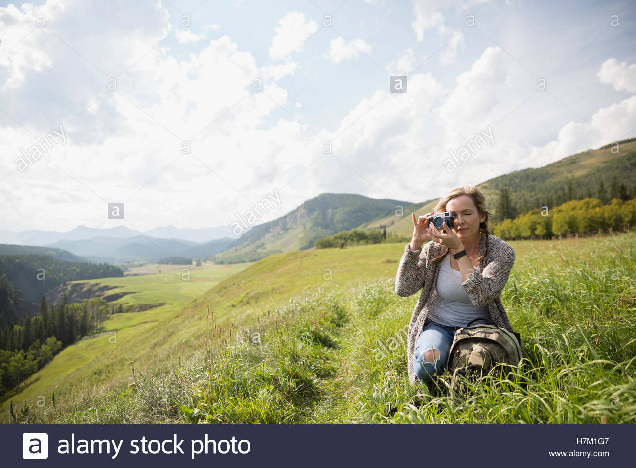 Woman hiking using camera in remote sunny rural field Stock Photo - Alamy