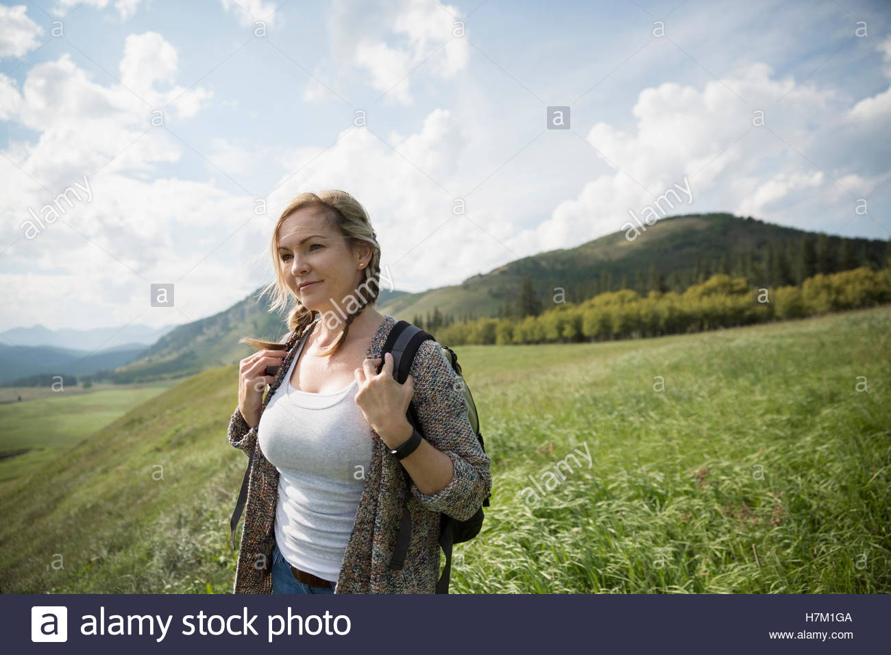 Woman with backpack hiking in remote sunny rural field Stock Photo - Alamy