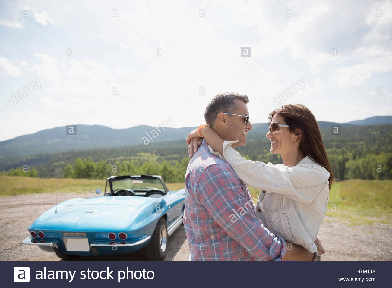 Affectionate couple hugging near convertible at rural overlook Stock ...