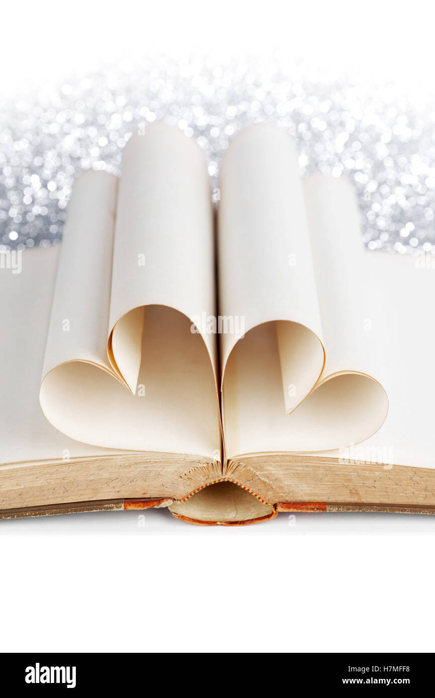 Pages of open book rolled in heart shape on glitter background Stock ...