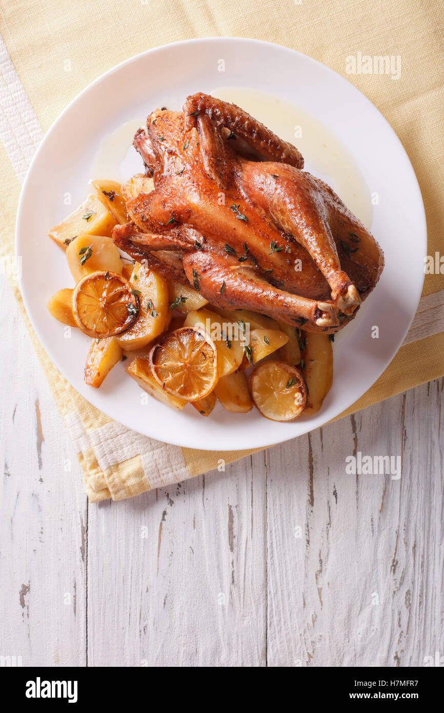 Lemon chicken with potato garnish on a plate on the table. vertical ...