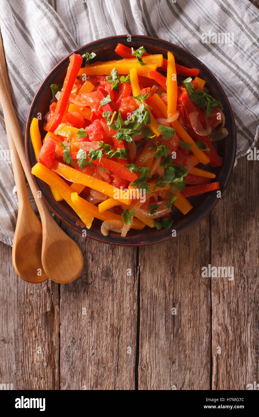 Stewed peppers with tomatoes and onions close up on a plate. vertical ...