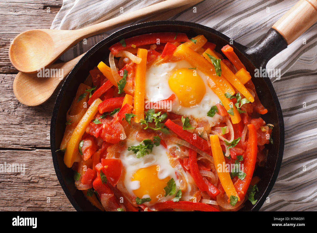 Basque breakfast: fried eggs with peppers in a pan close-up. Horizontal ...