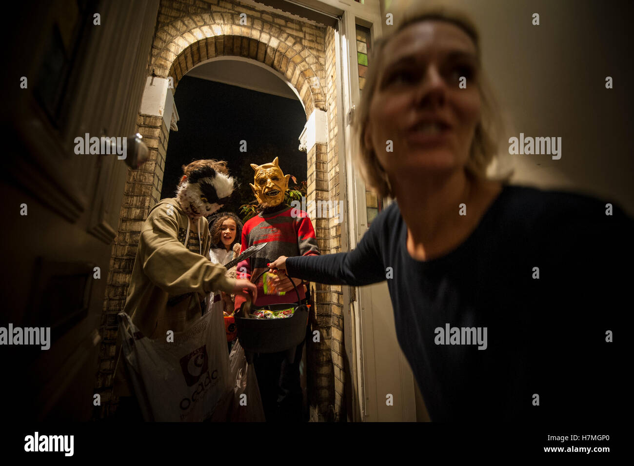 A woman answers the door to Halloween Trick or Treaters Stock Photo - Alamy