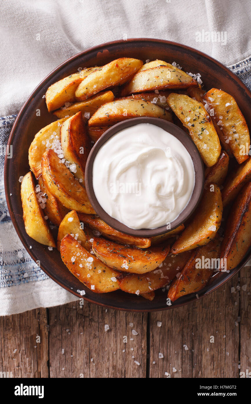 Tasty potato wedges with herbs and mayonnaise on a plate closeup on the ...