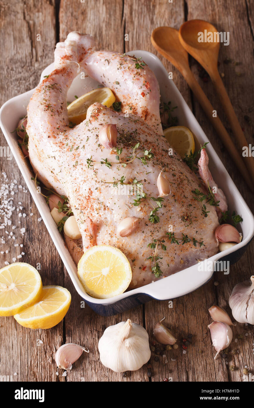 raw whole chicken marinated with garlic, thyme and lemon close-up on ...