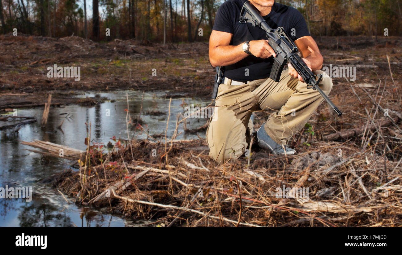 Man with an AR-15 and handgun kneeling next to some water Stock Photo ...