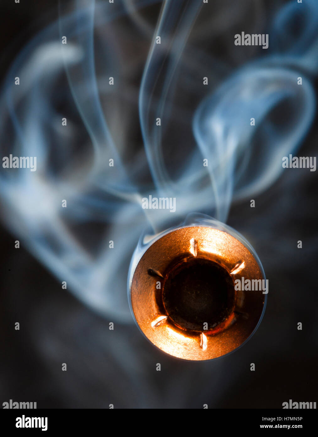 Hollow point bullet with copper plating and smoke on a black background ...