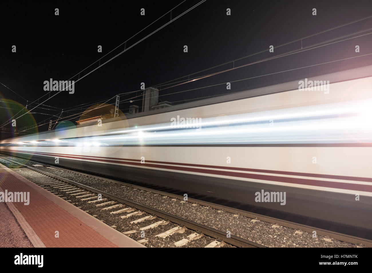 Fast train passing through a railway station at night (motion blurred ...