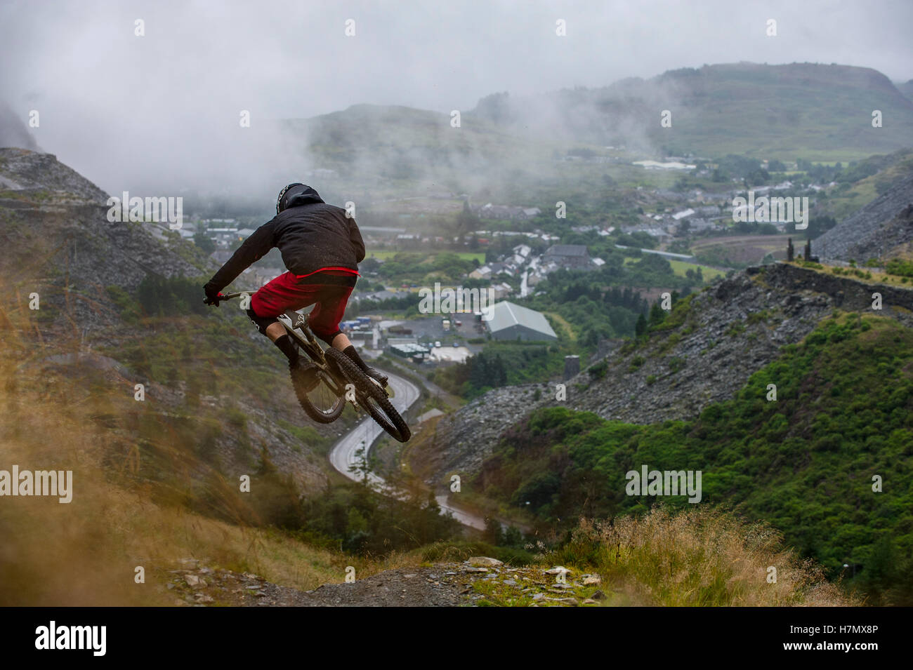 A mountain biker jumps a rock drop at Antur Stiniog mountain bike ...