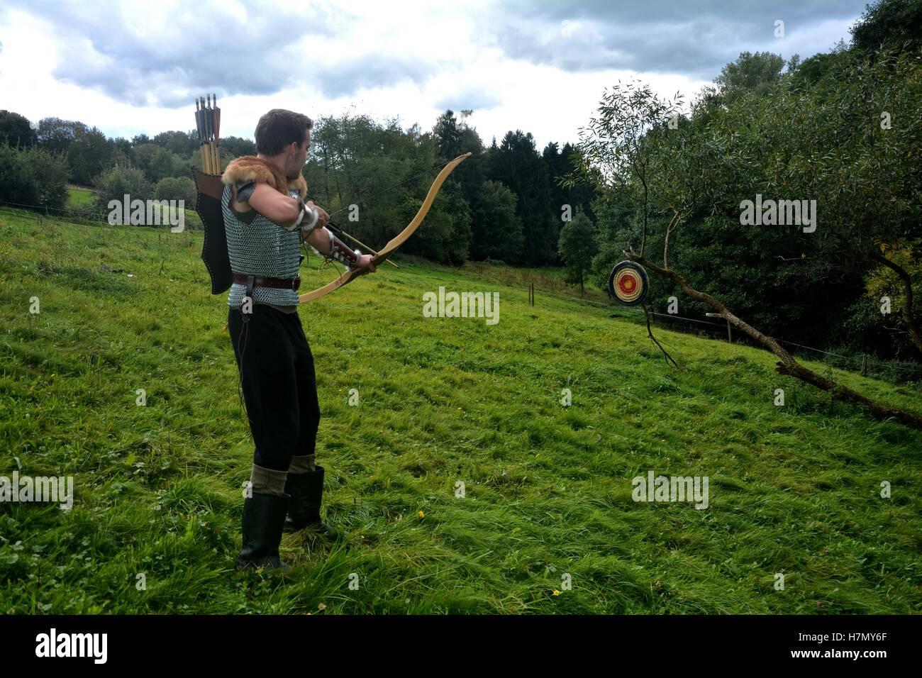 Young medieval archer of the side, aims with arrow and curve at straw ...