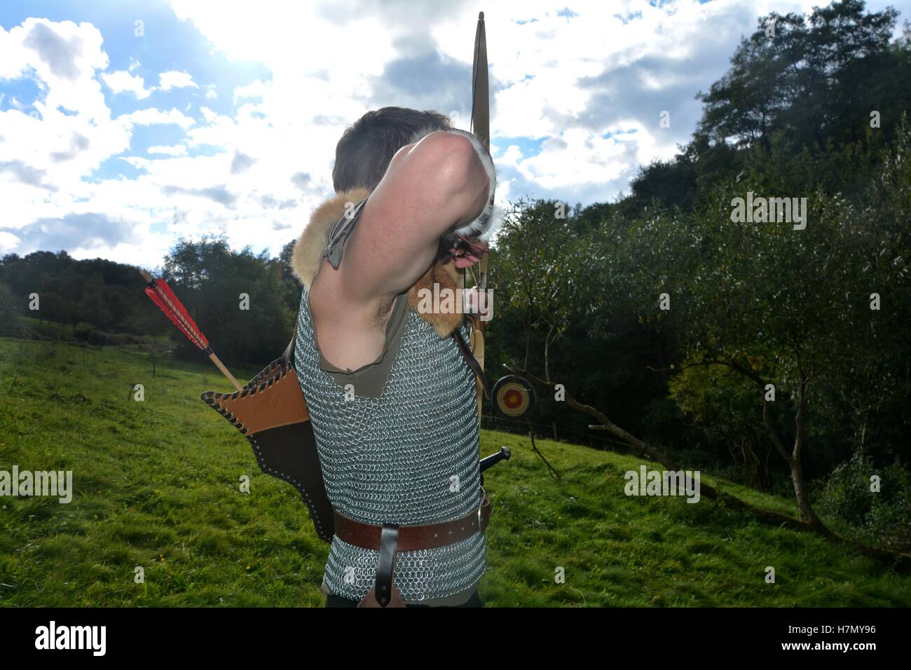 Young medieval archer from the back, aims with arrow and curve at straw ...