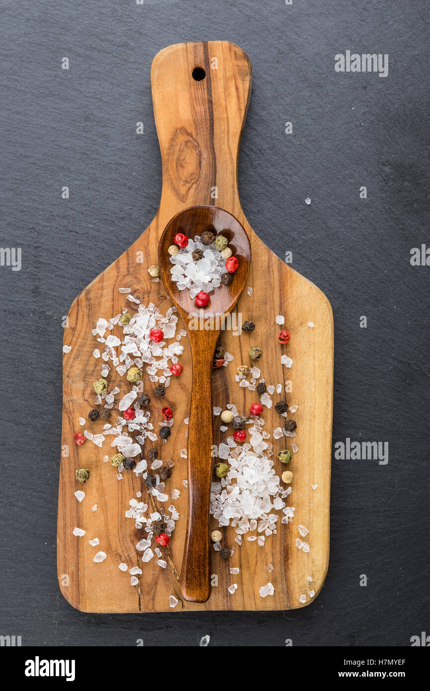 Different types of salt and pepper and scattered wooden spoon on ...