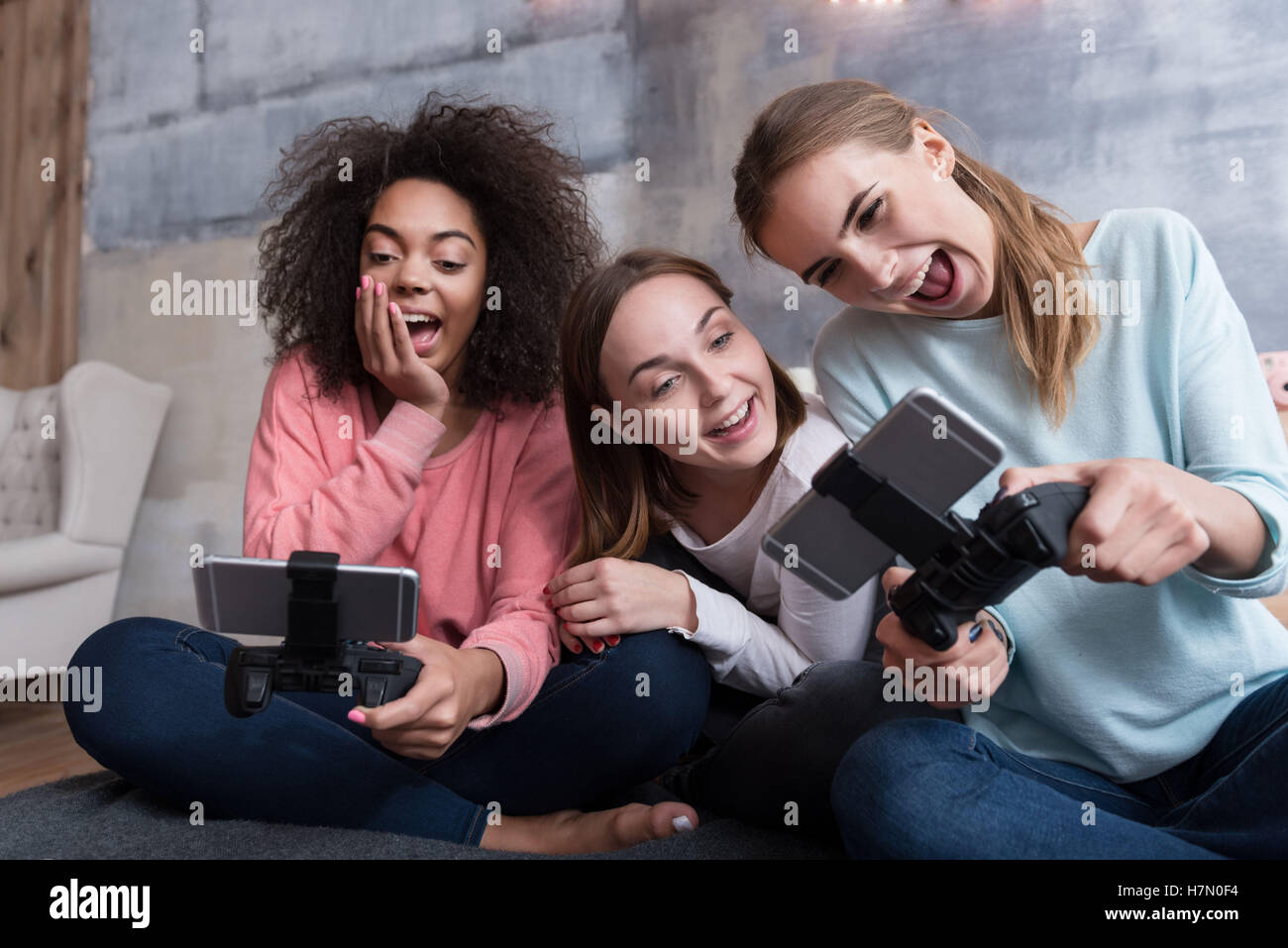 Laughing girls holding game consoles and playing games Stock Photo - Alamy