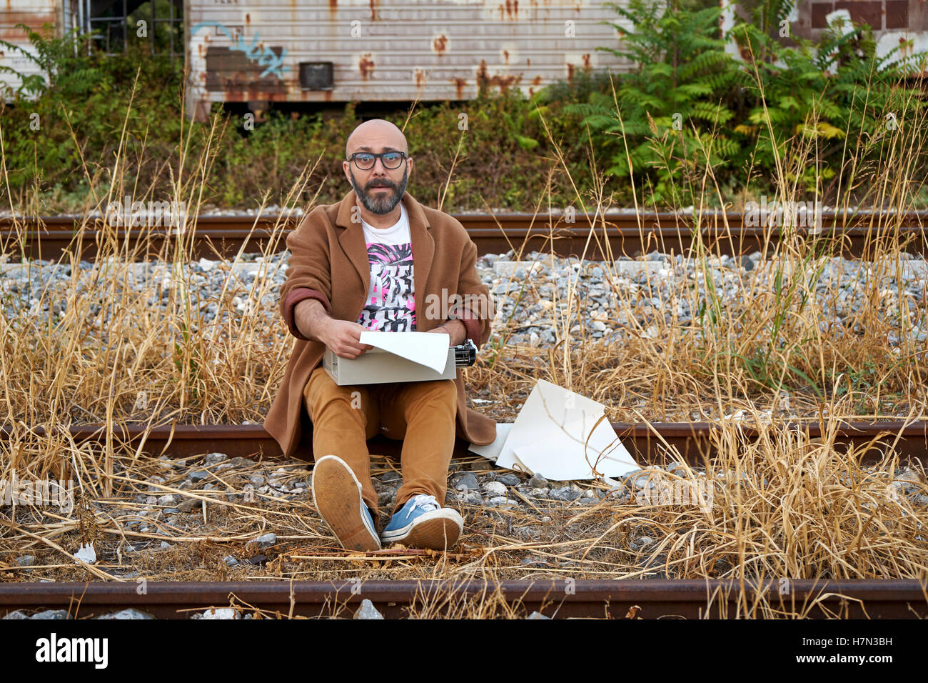 Concept with a man sitting in the train rail and typing on a typewriter ...