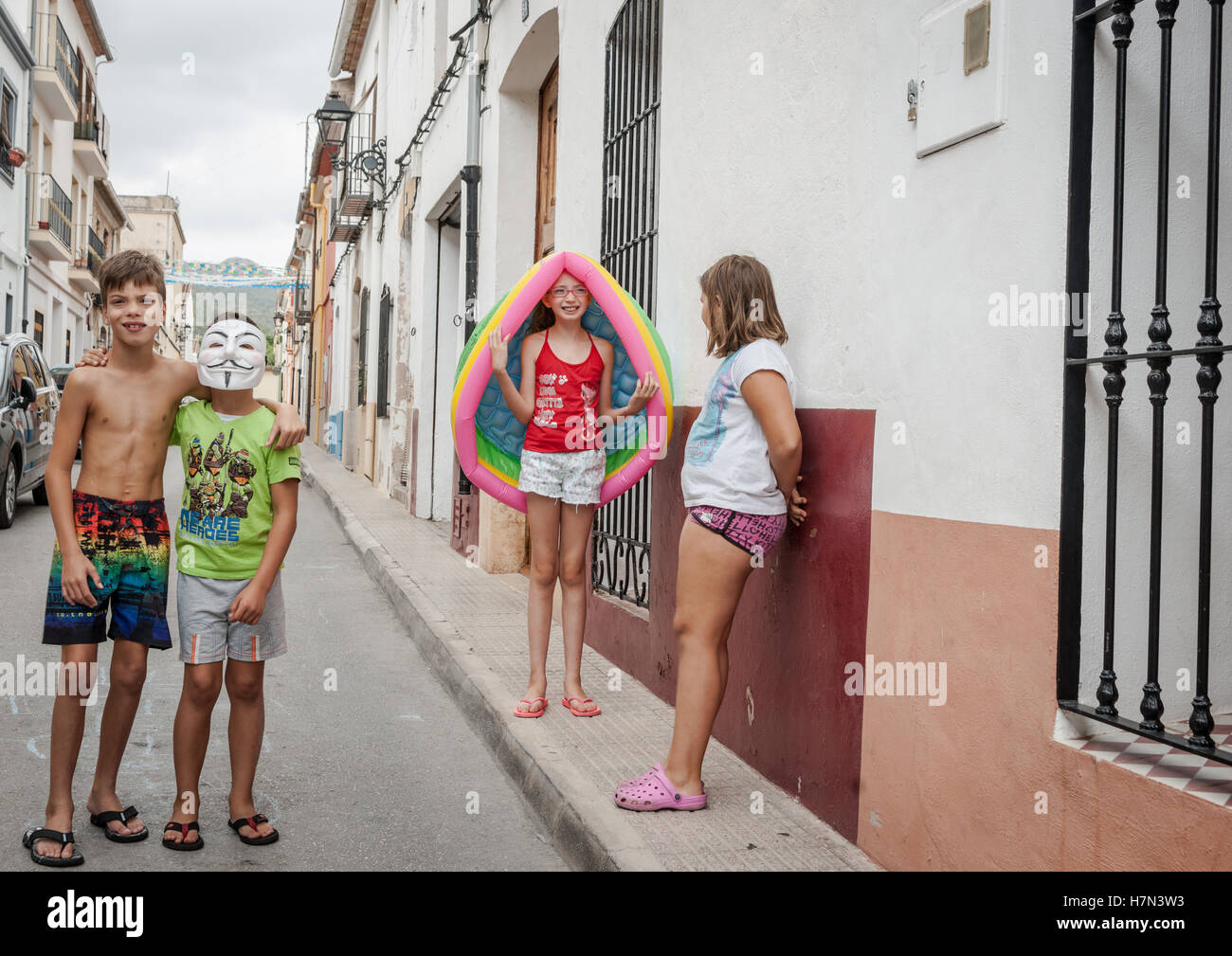 Four Spanish children acting up for camera in the narrow village street ...
