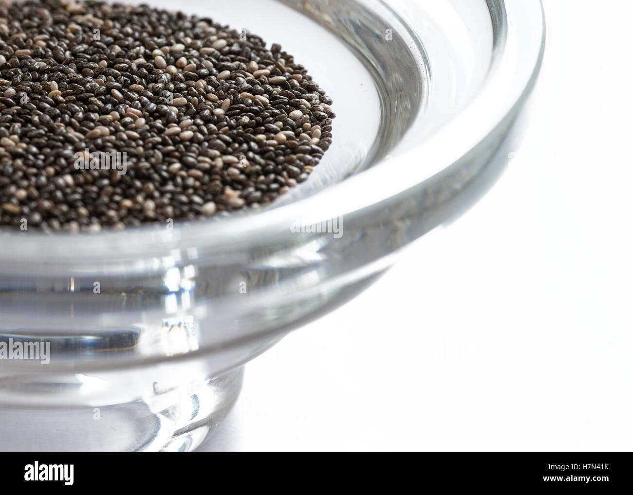 side view of chia seeds in a thick round glass bowl on a white ...