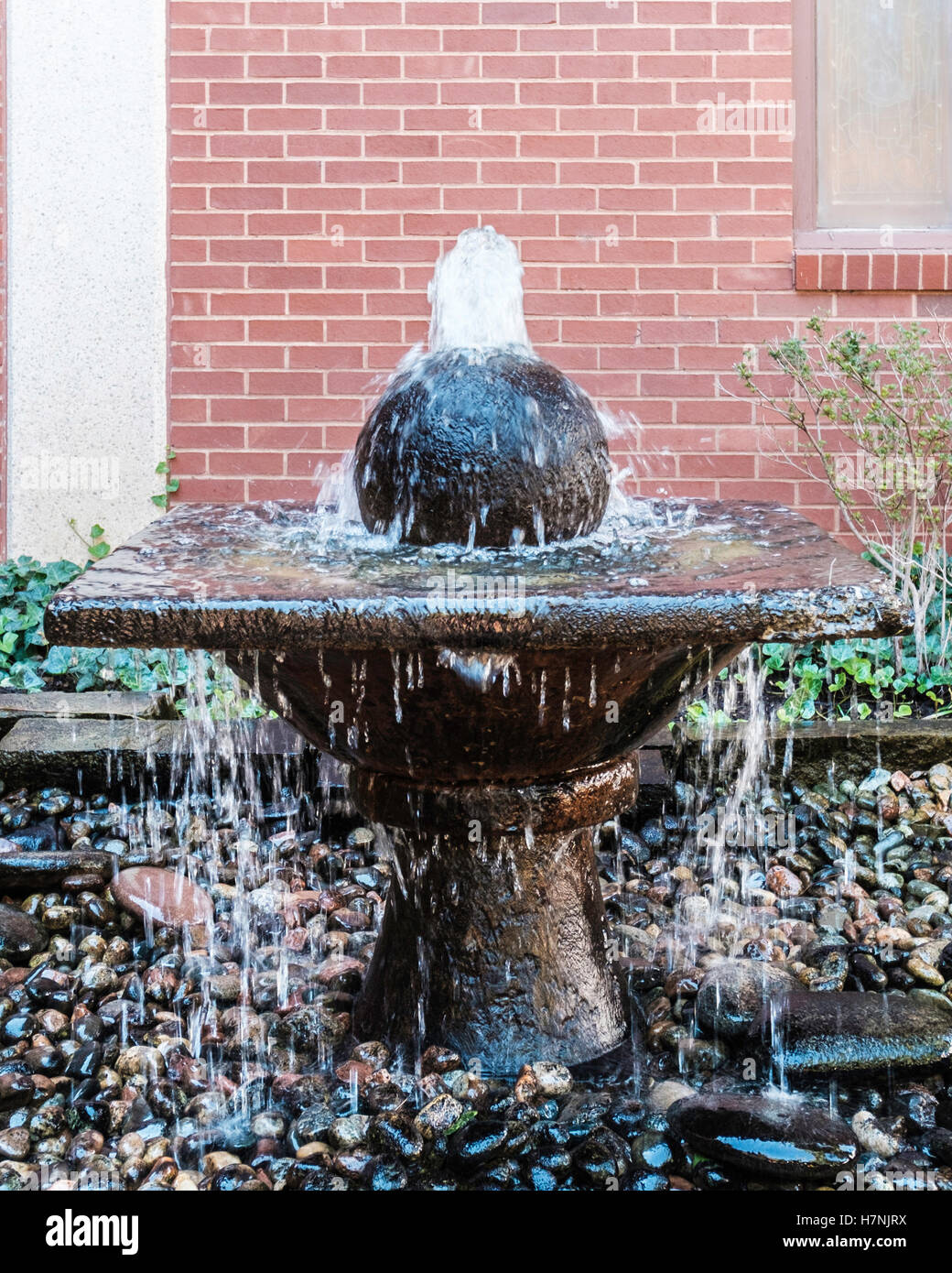 A decorative flowing water fountain sat on a pedestal with a ball ...