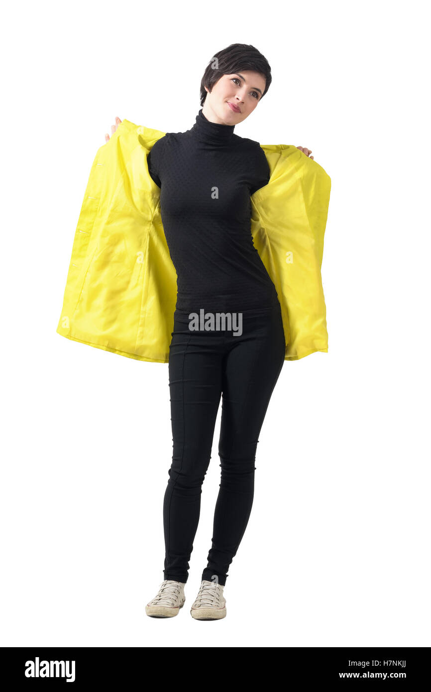 Young elegant woman in black clothes taking off yellow rain coat. Full ...