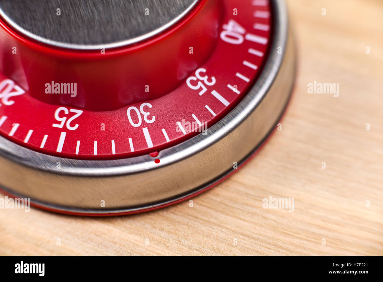 Macro view of a red kitchen egg timer showing 30 minutes on wooden ...