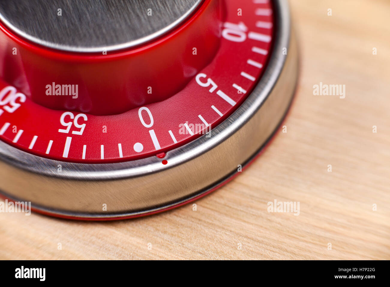 Macro view of a red kitchen egg timer showing 0 minutes on wooden ...