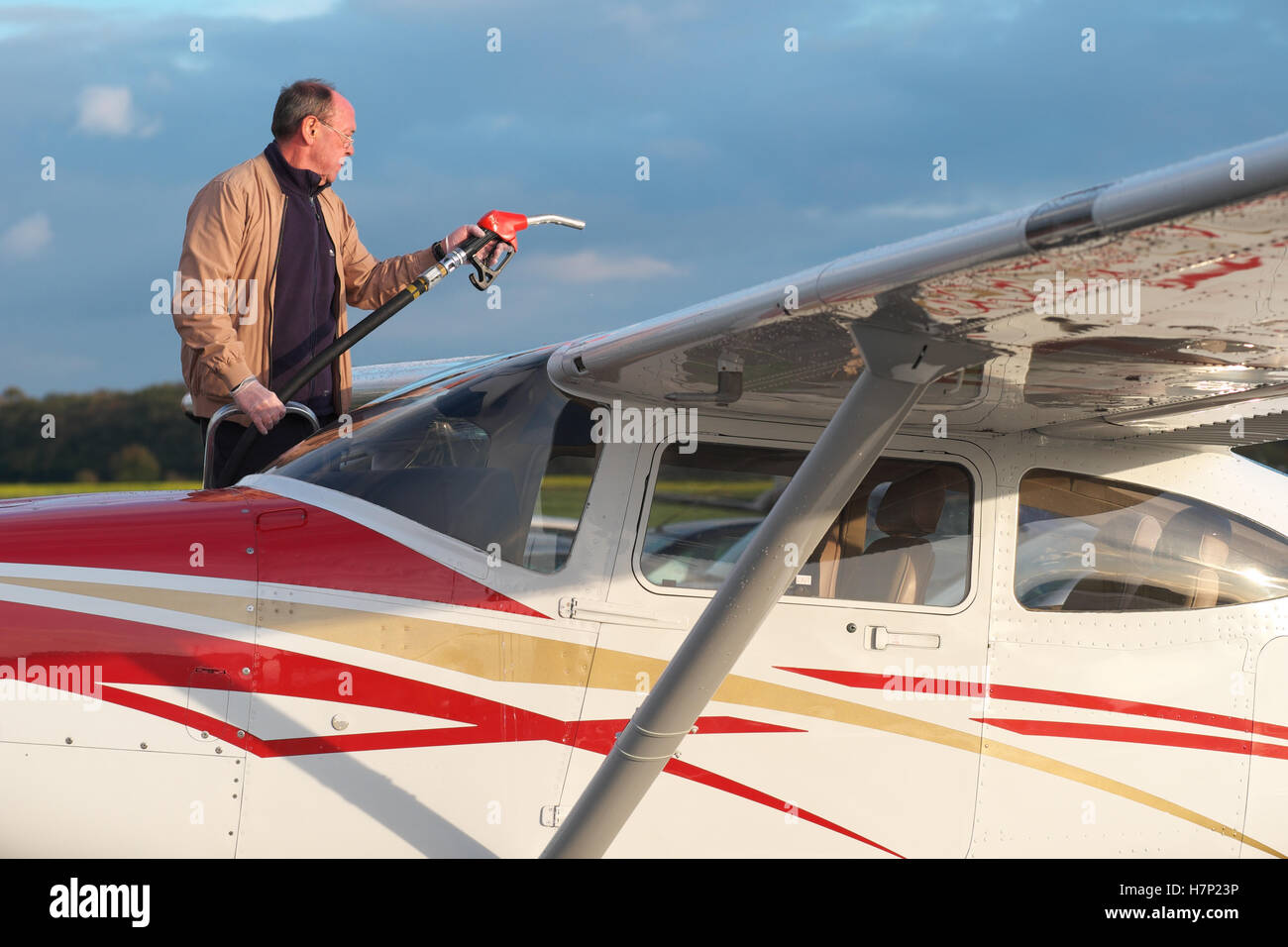 A pilot uses a step ladder to refuel his Cessna 182 Skylane light aircraft in the late afternoon ...