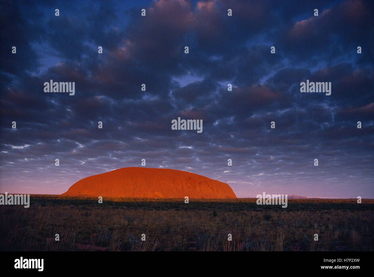 Ayers Rock at sunset with cloudy sky, Uluru-Kata Tjuta National Park ...