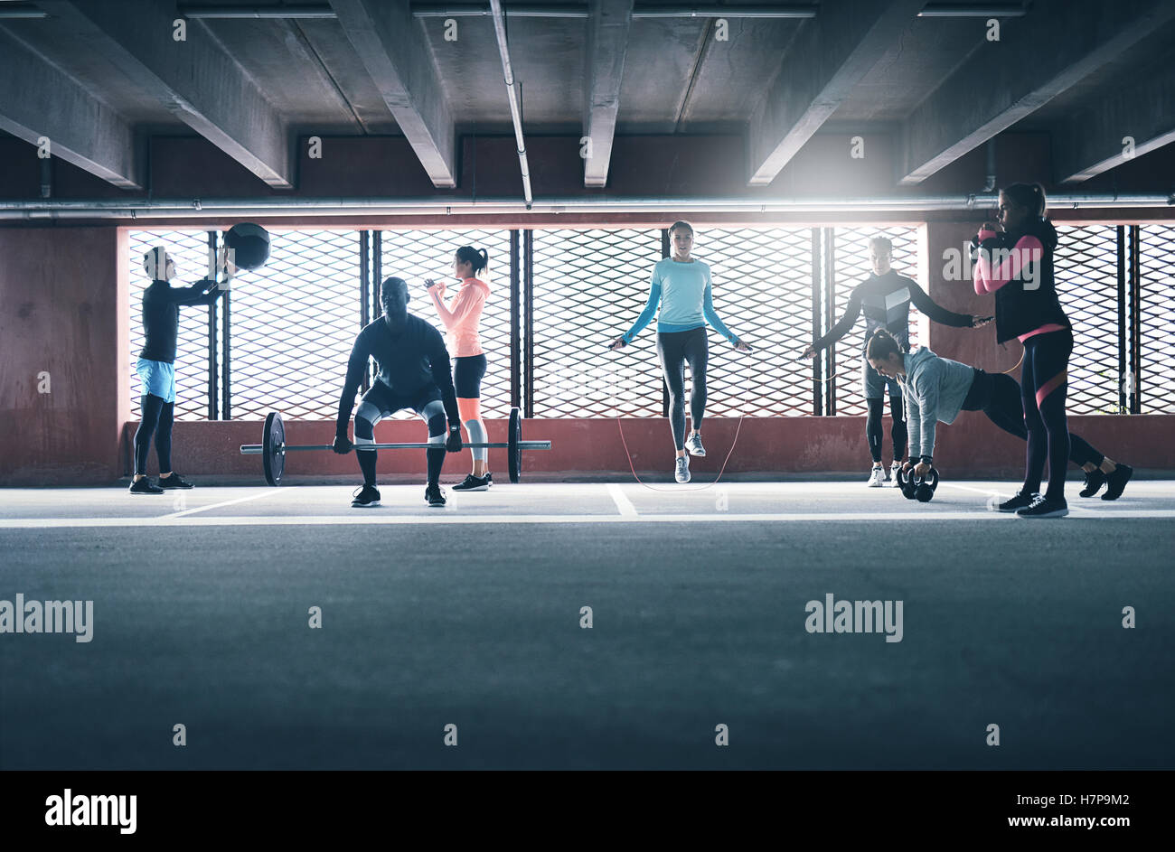 Group of people exercising together, lifting weight using skipping rope ...