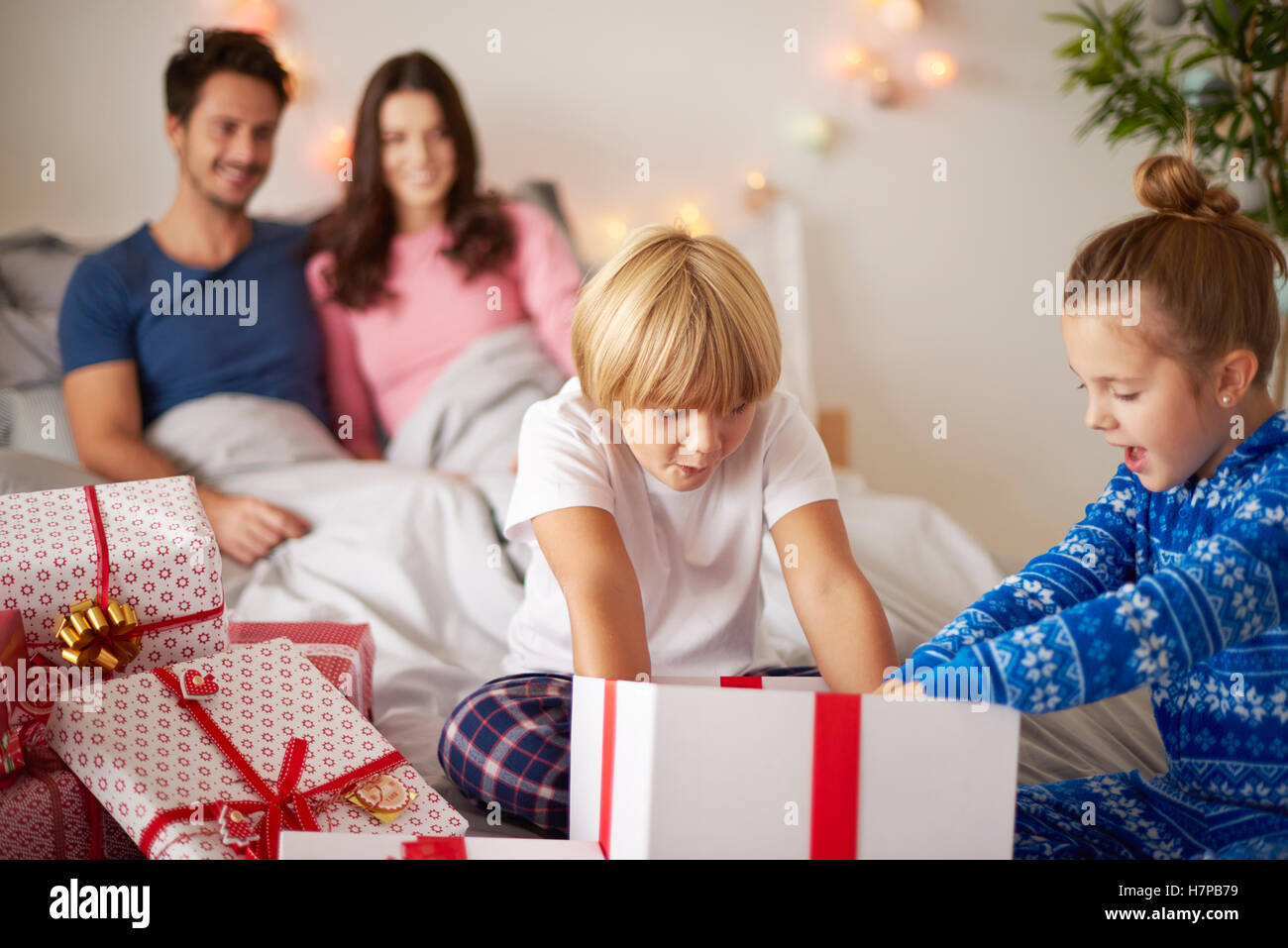 Kids opening Christmas presents in the bed Stock Photo - Alamy