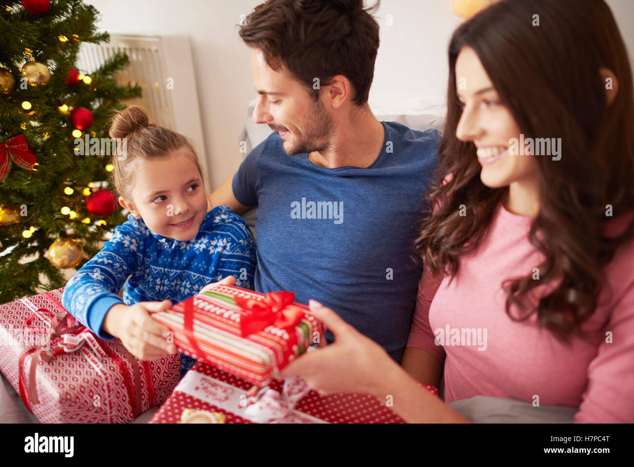 Family sharing the Christmas presents in the bed Stock Photo - Alamy
