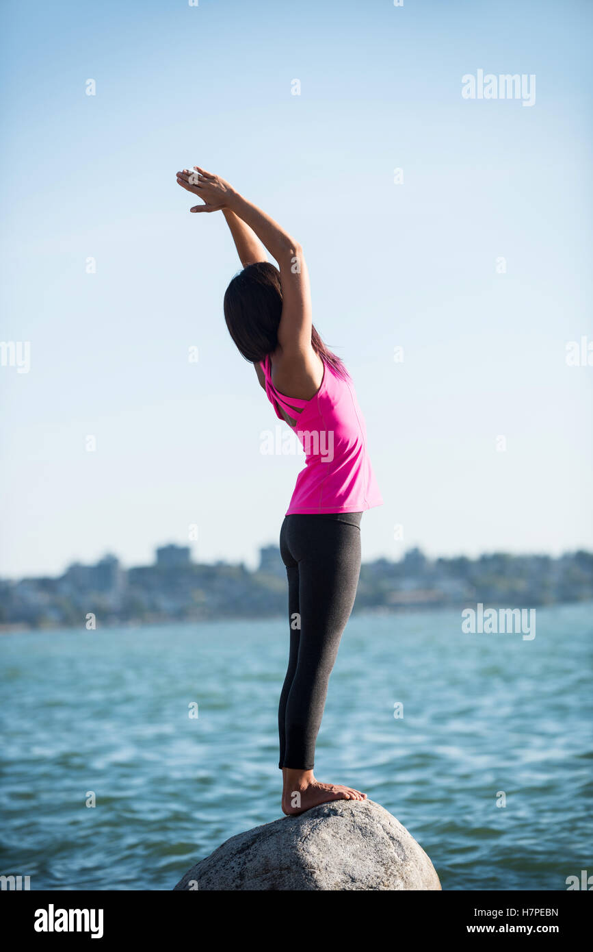 Woman performing yoga on rock Stock Photo - Alamy