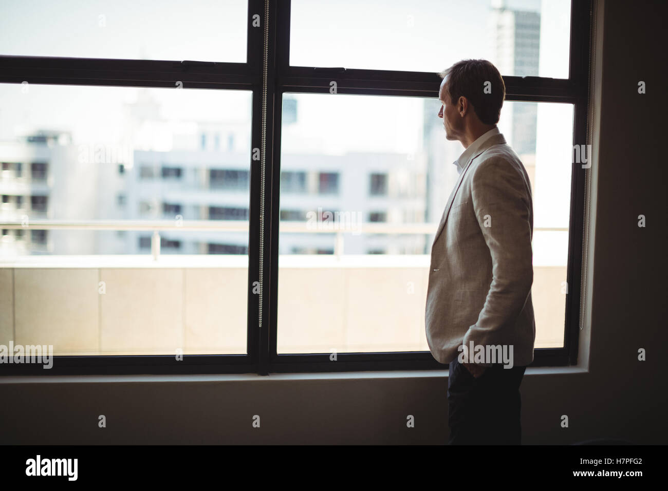 Thoughtful businessman looking through window Stock Photo - Alamy