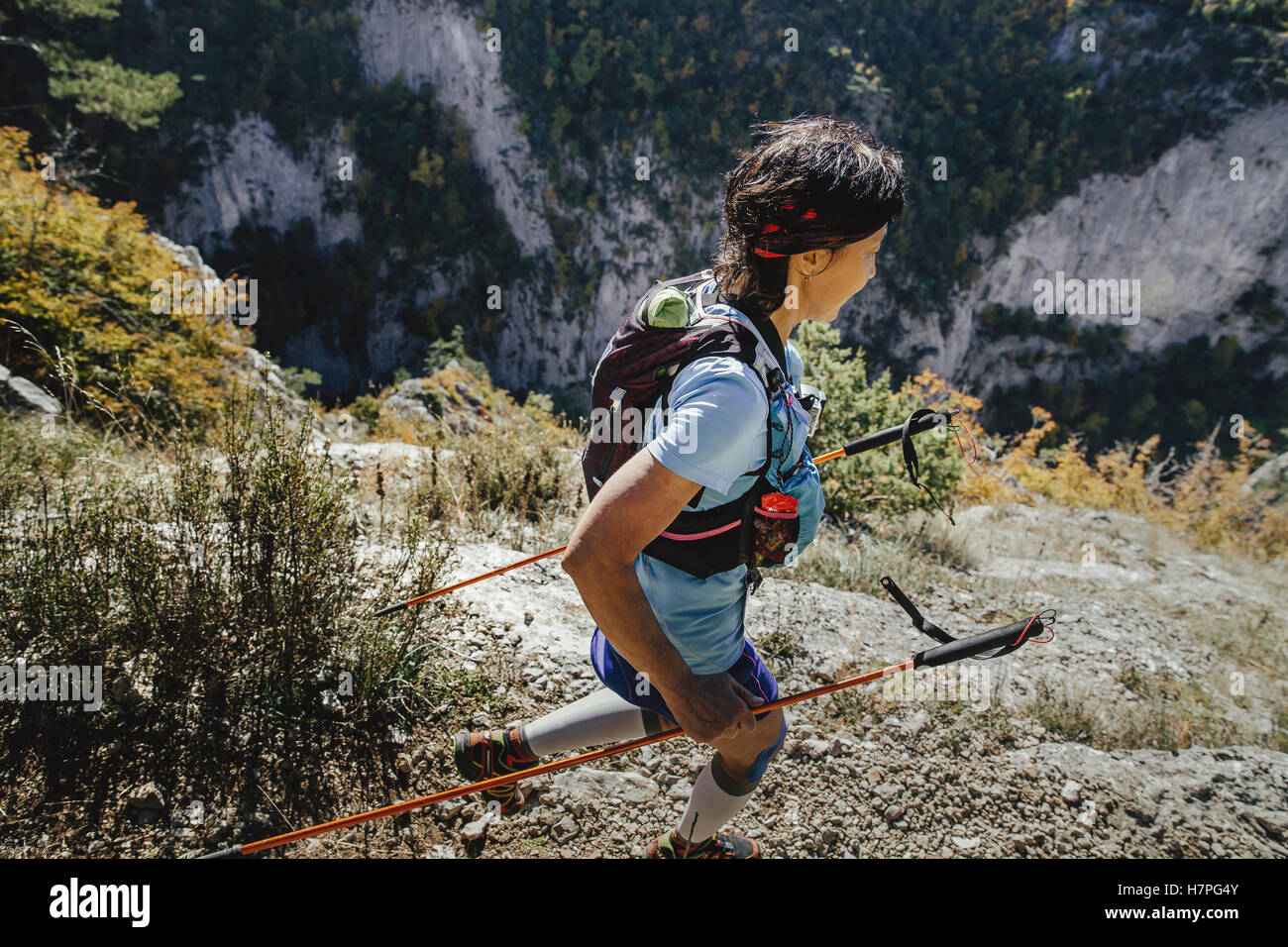 closeup young woman runner with walking poles running steep cliff ...