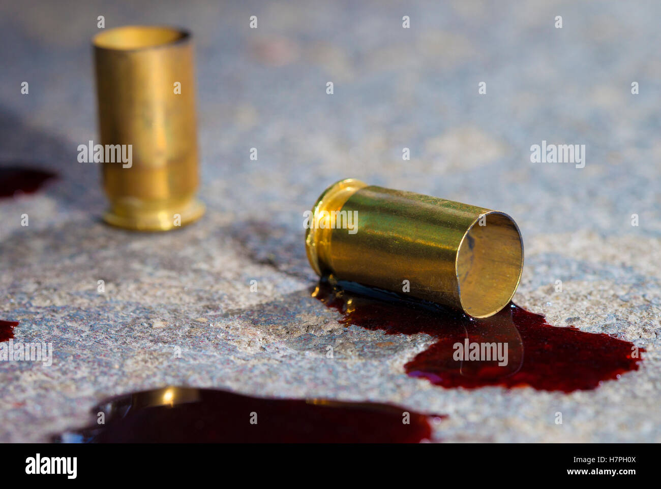Two pieces of handgun brass on concrete with blood Stock Photo - Alamy