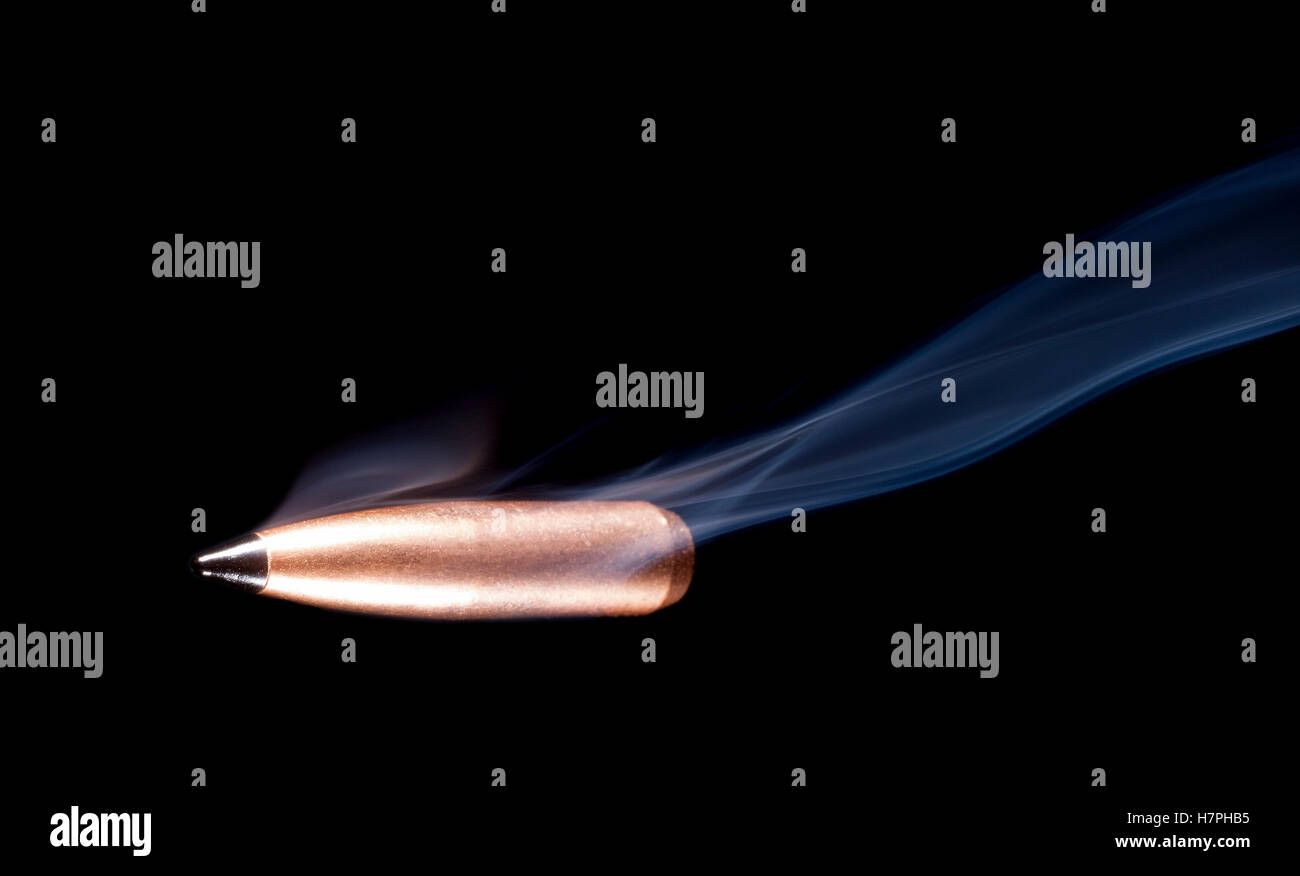 Bronze colored bullet with a black polymer tip and smoke behind Stock ...