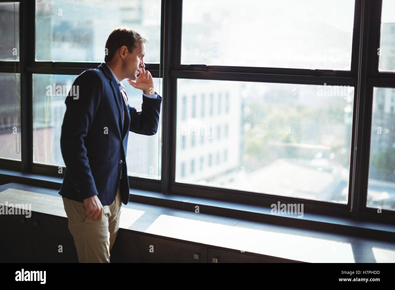 Businessman looking through window while talking on the phone Stock ...