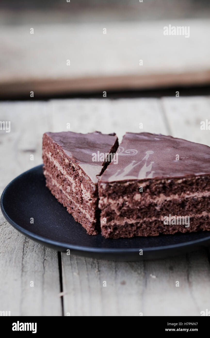 Cut of chocolate layer cake with chocolate cream and glaze on a dark ...