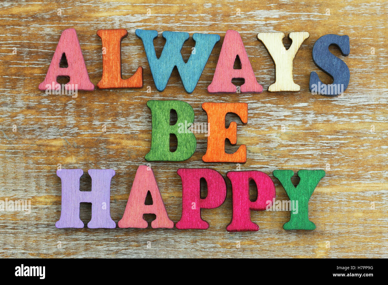 Always be happy written with colorful wooden letters on rustic surface ...