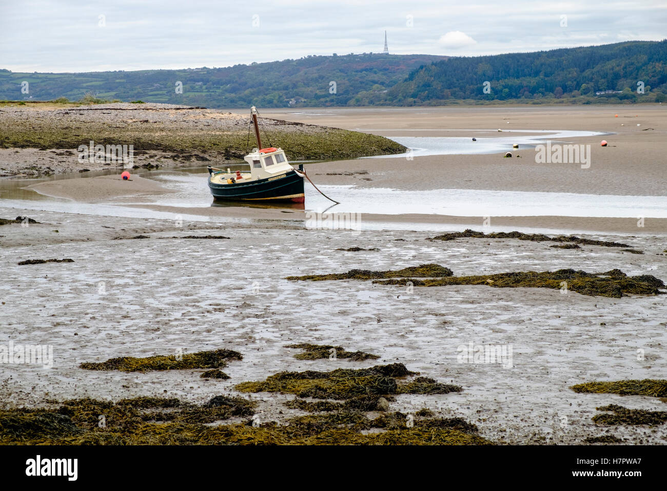 Fishing boat stranded in shallow water channel at low tide in Red Wharf ...