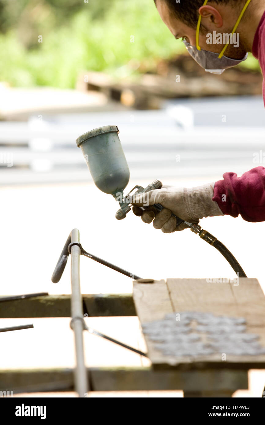 craftsman painting an iron gate with a spray machine Stock Photo - Alamy