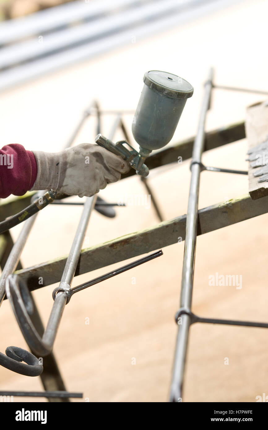craftsman painting an iron gate with a spray machine Stock Photo - Alamy