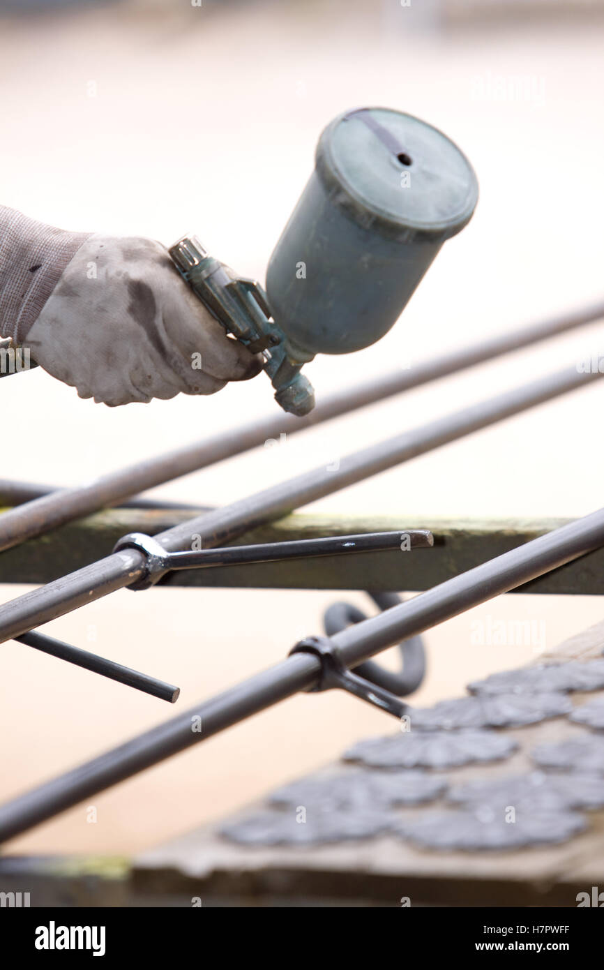 craftsman painting an iron gate with a spray machine Stock Photo - Alamy