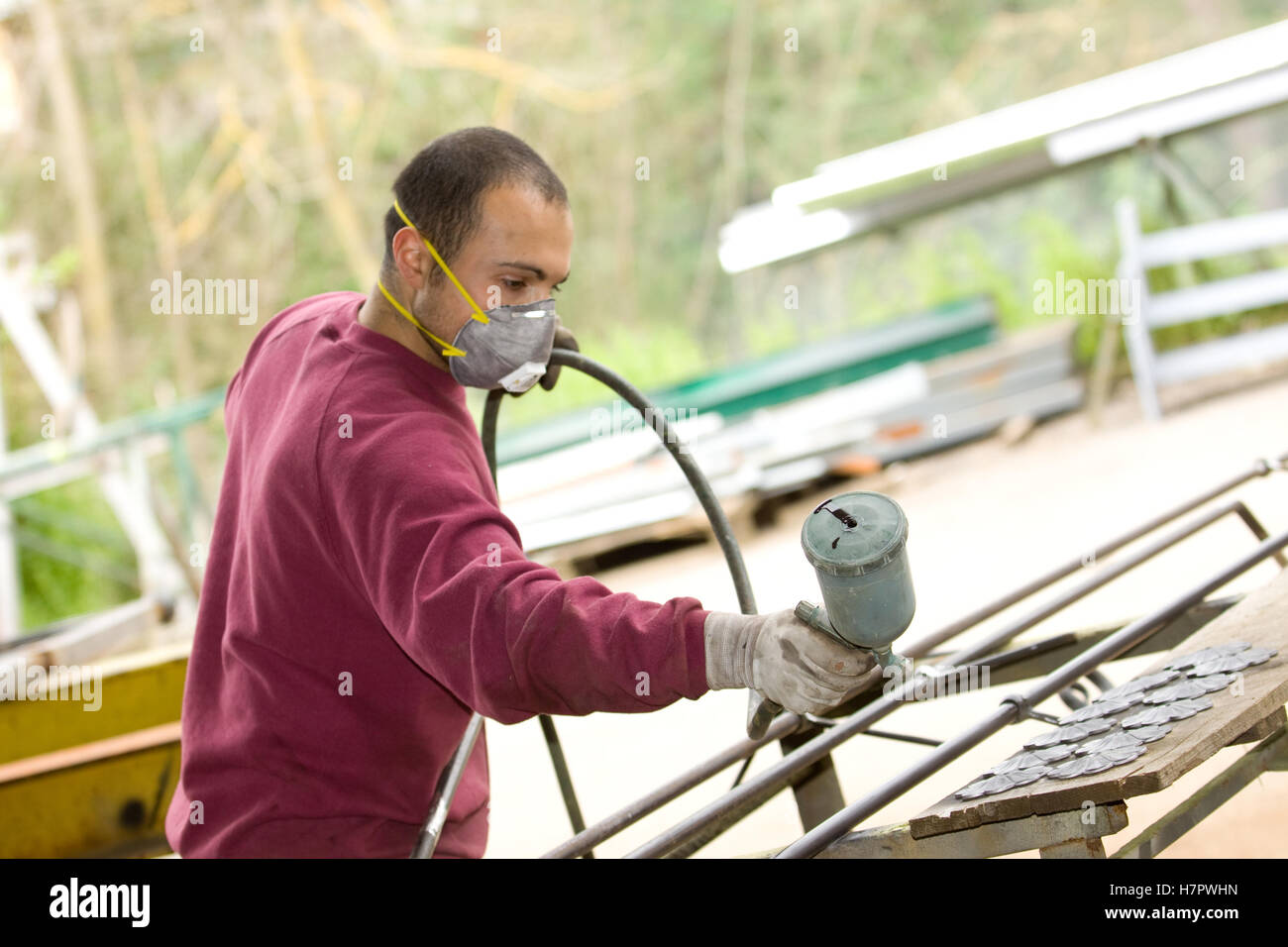 craftsman painting an iron gate with a spray machine Stock Photo - Alamy