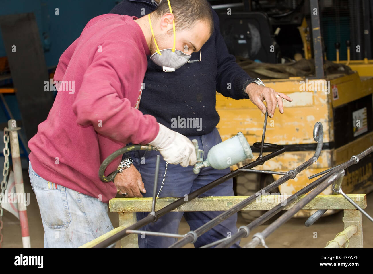 craftsman painting an iron gate with a spray machine Stock Photo - Alamy