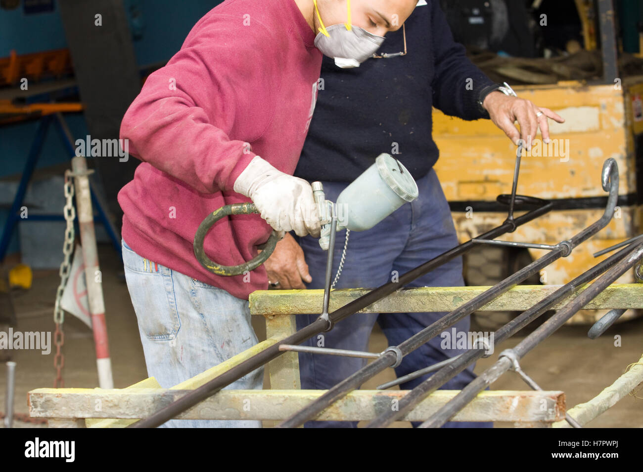 craftsman painting an iron gate with a spray machine Stock Photo - Alamy