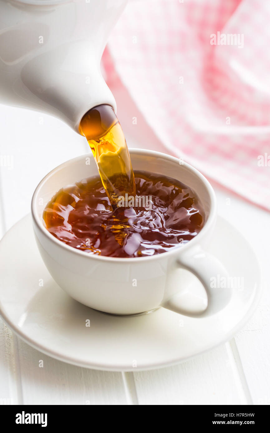 Pouring tea from teapot into a cup Stock Photo - Alamy